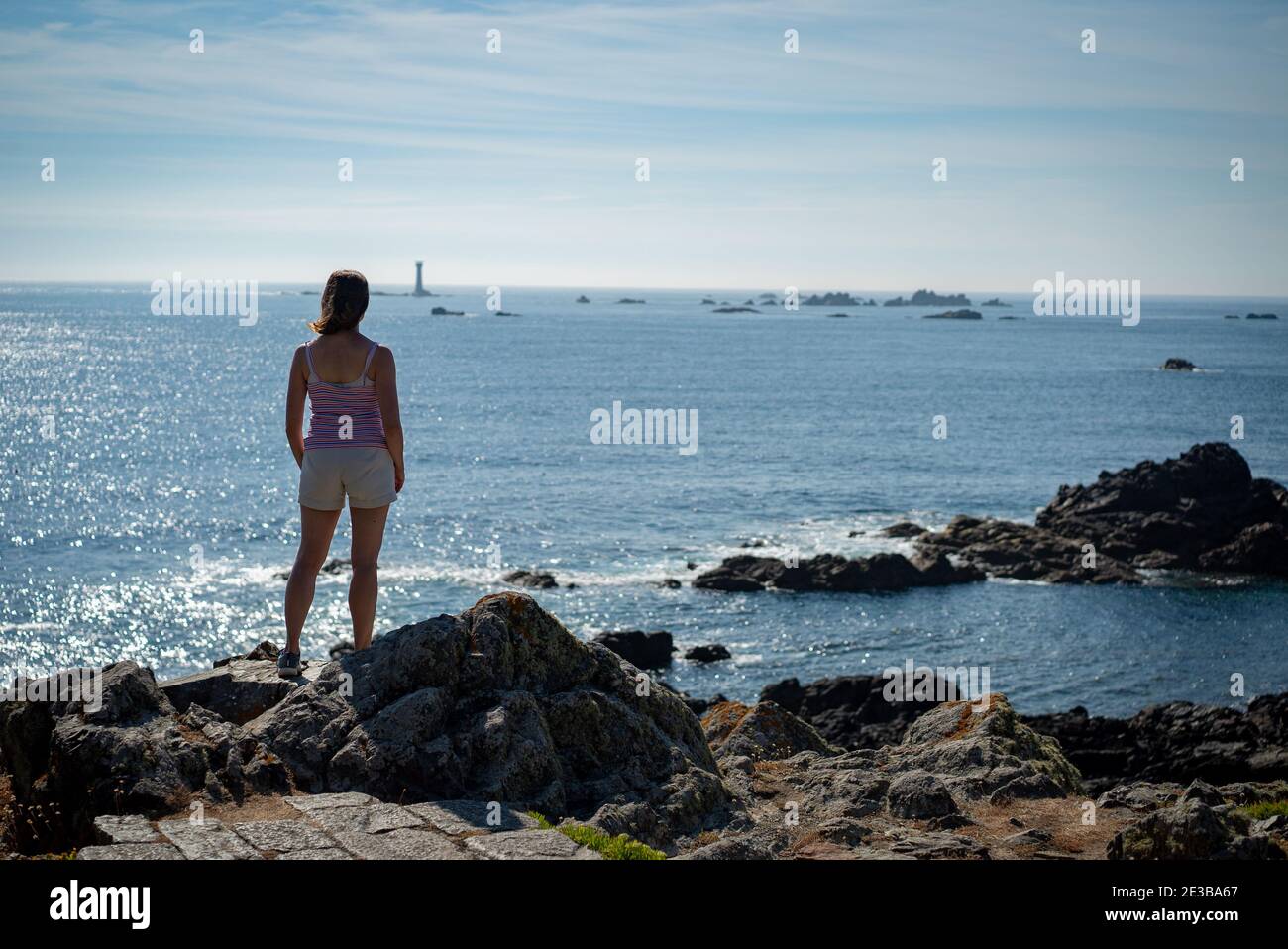 Unrecognizabe woman admiring the Les Hanois Lighthouse on the island of ...