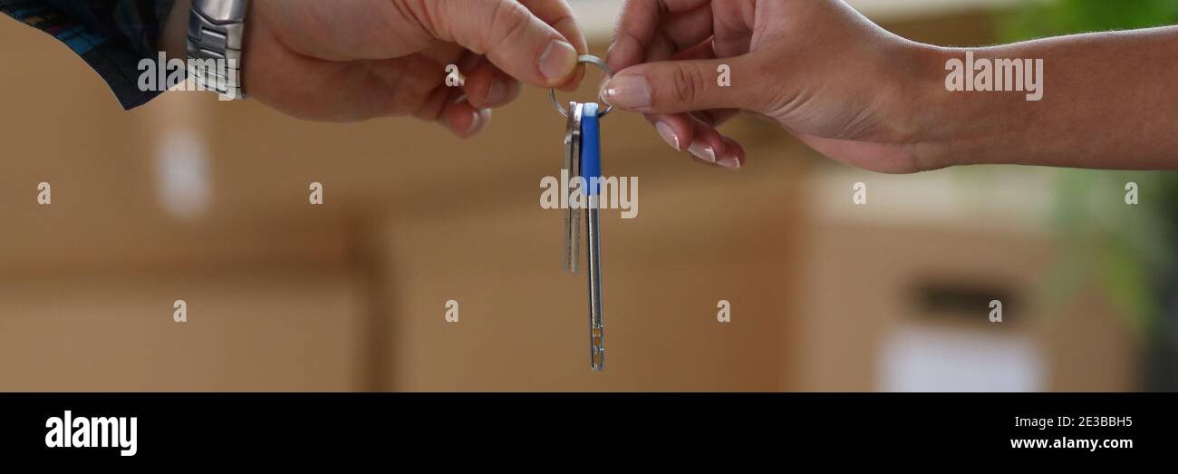 Male hand give key to female hand on background of box Stock Photo - Alamy
