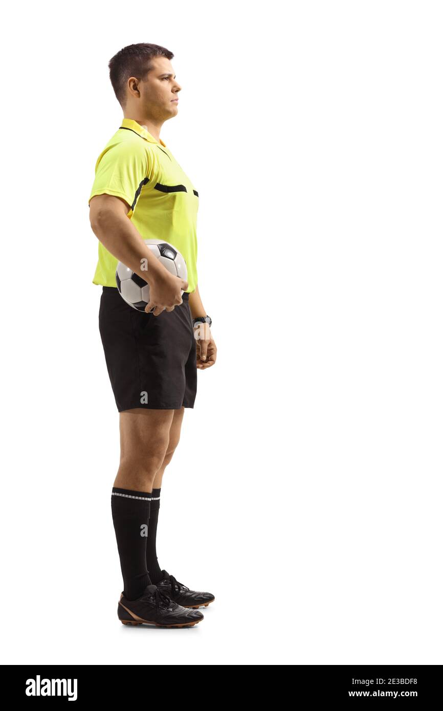 Full length profile shot of a footall referee holding a ball under arm ...