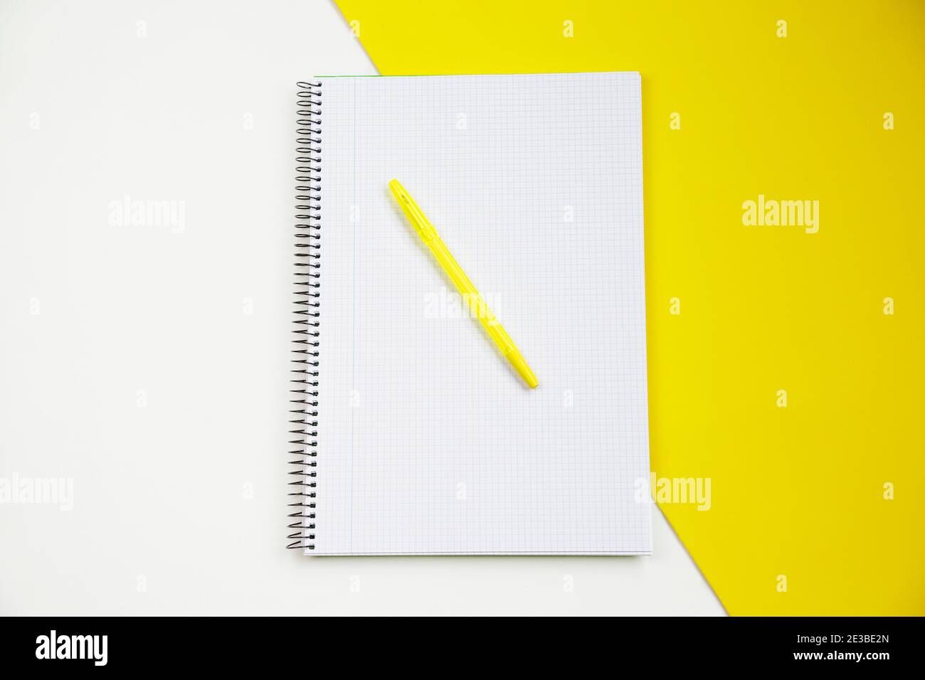 Top view of an open notebook and a pen against white and yellow ...