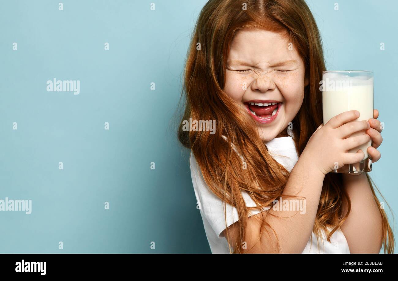 Cute red hair girl child kid drinking milk or kefir screaming joyfully ...