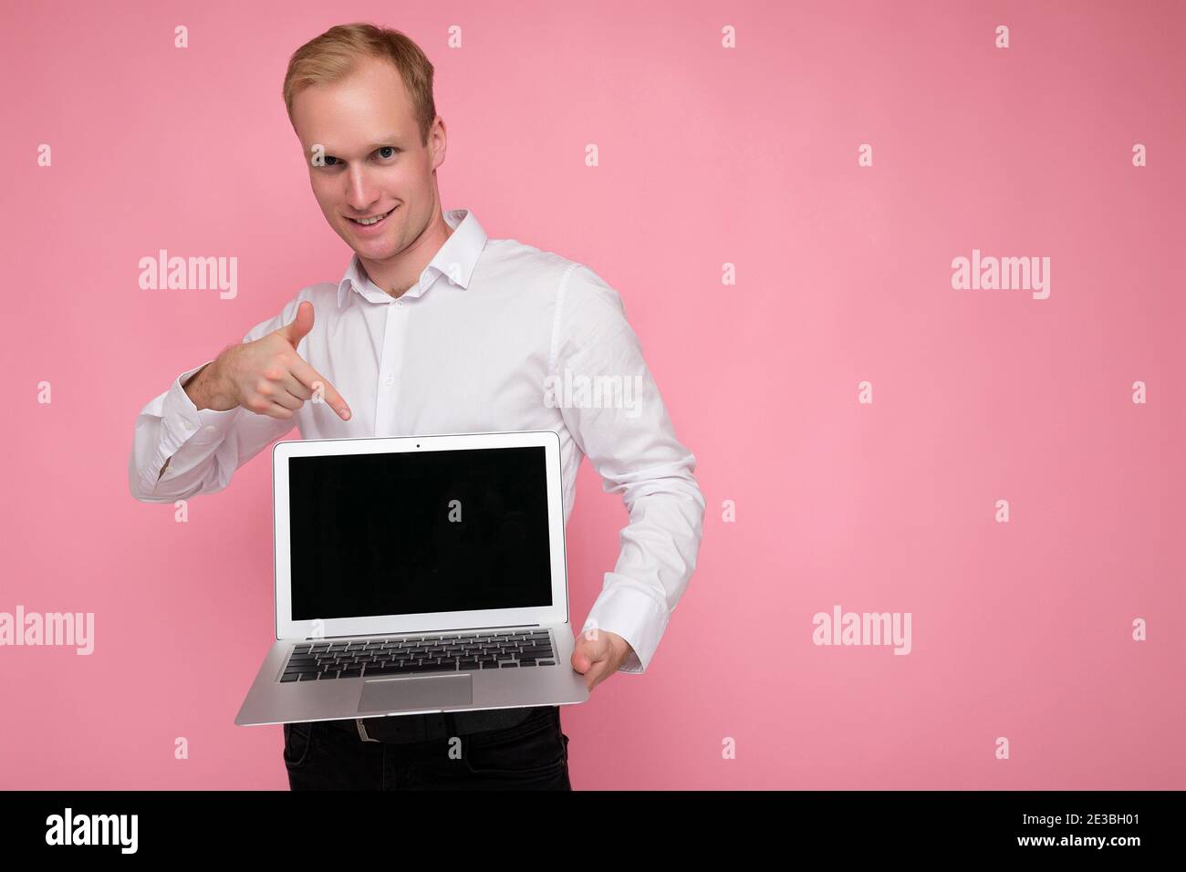 Photo shot of handsome smiling blonde man holding computer laptop with ...
