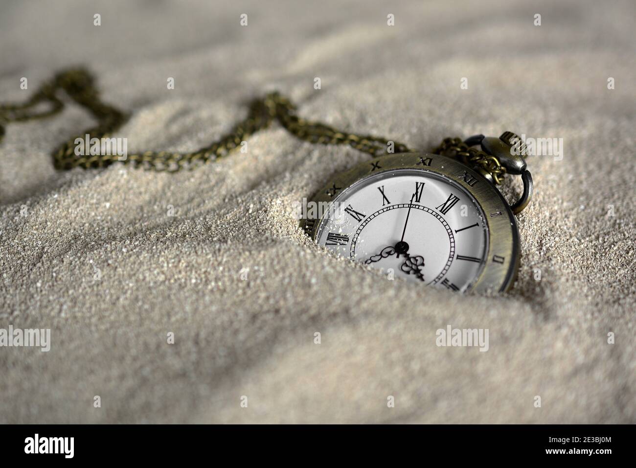 Old pocket watch half buried in sand. Old pocket watch lost in sand ...