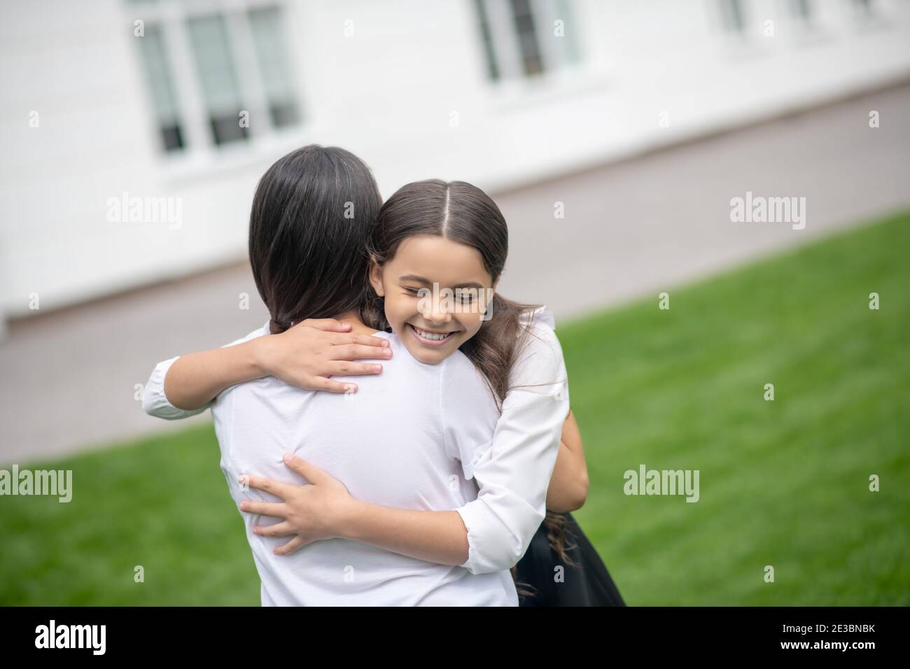Daughter hugging tightly mom in the schoolyard Stock Photo - Alamy