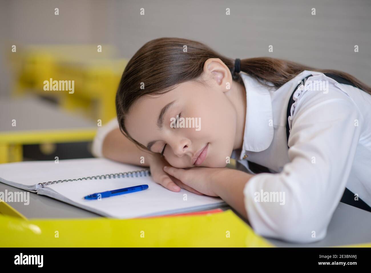 Schoolgirl with closed eyes resting head on desk Stock Photo - Alamy