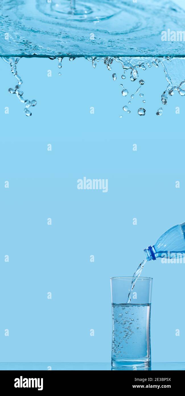 Pouring clean drinking water from blue plastic bottle into glass on ...