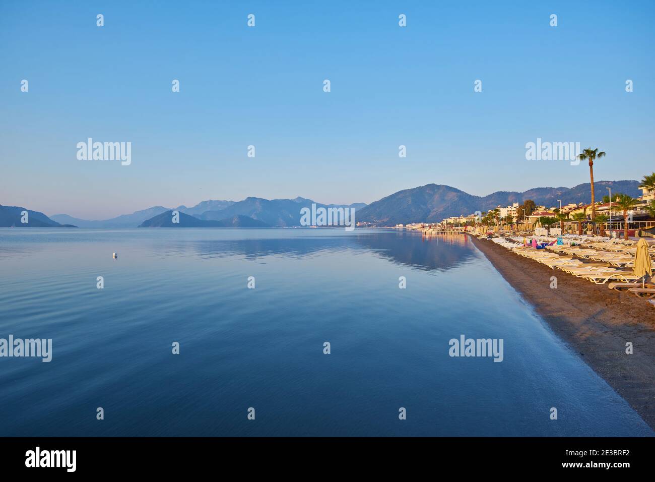 sandy beach without people and with sun loungers, umbrellas, palm trees ...