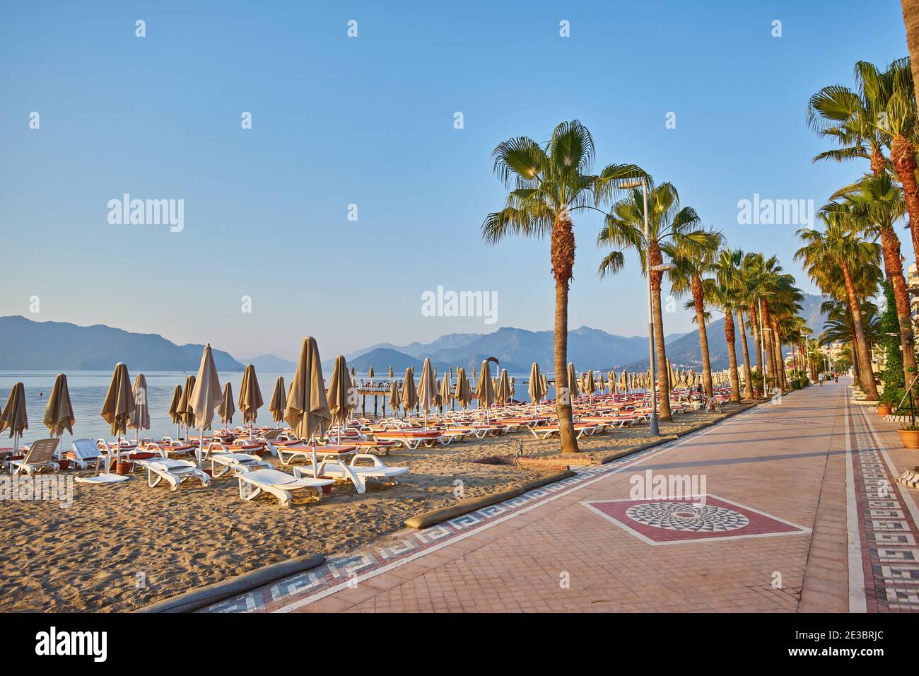 sandy beach without people and with sun loungers, folded umbrellas ...