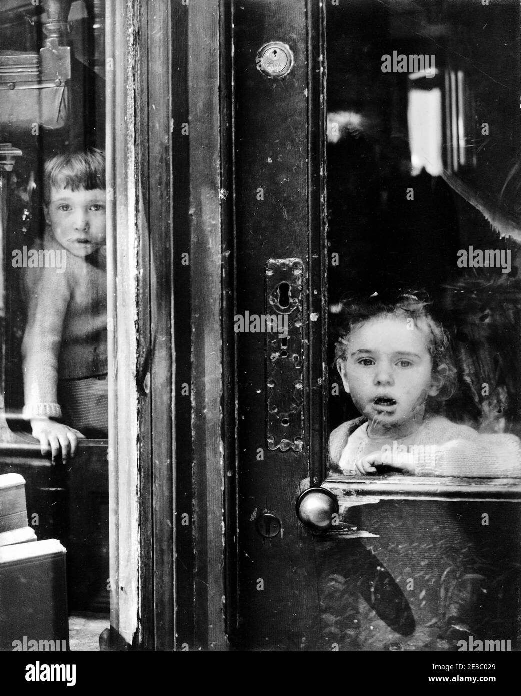 Two young children peering out of window in Caldmore, Walsall, Britain ...