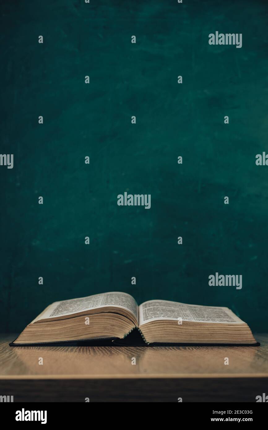 Open holy bible on a wooden table. Beautiful green wall background ...