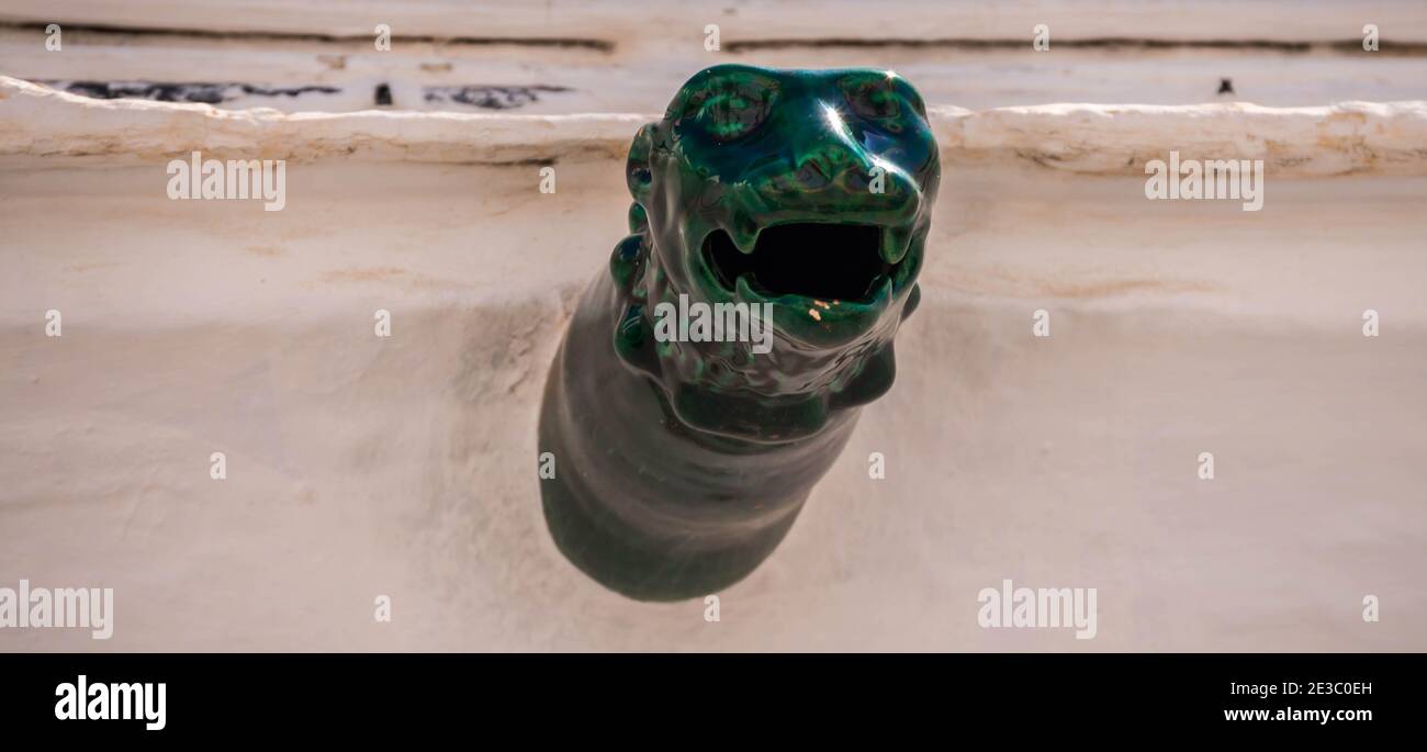 Ceramic green gargoyle on a white wall, an interesting traditional ...