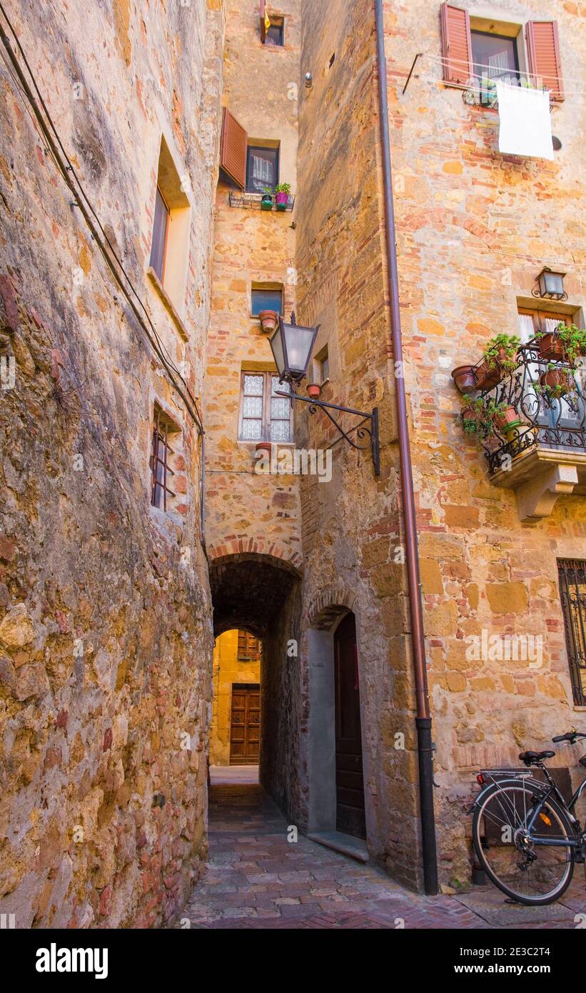 An alleyway through an historic stone building in the village of Pienza ...