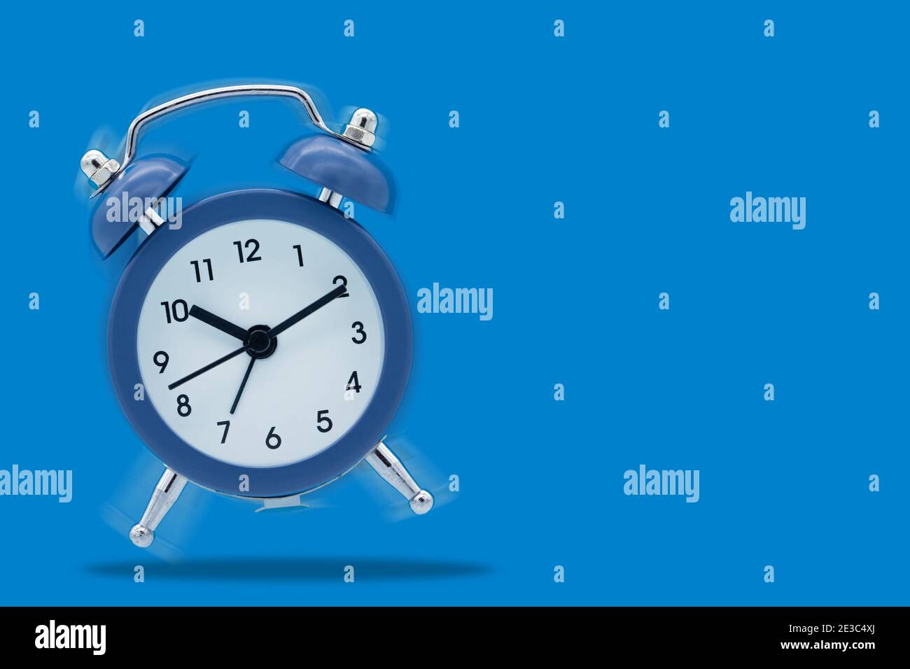 Classic alarm clock ringing isolated on blue background Stock Photo - Alamy