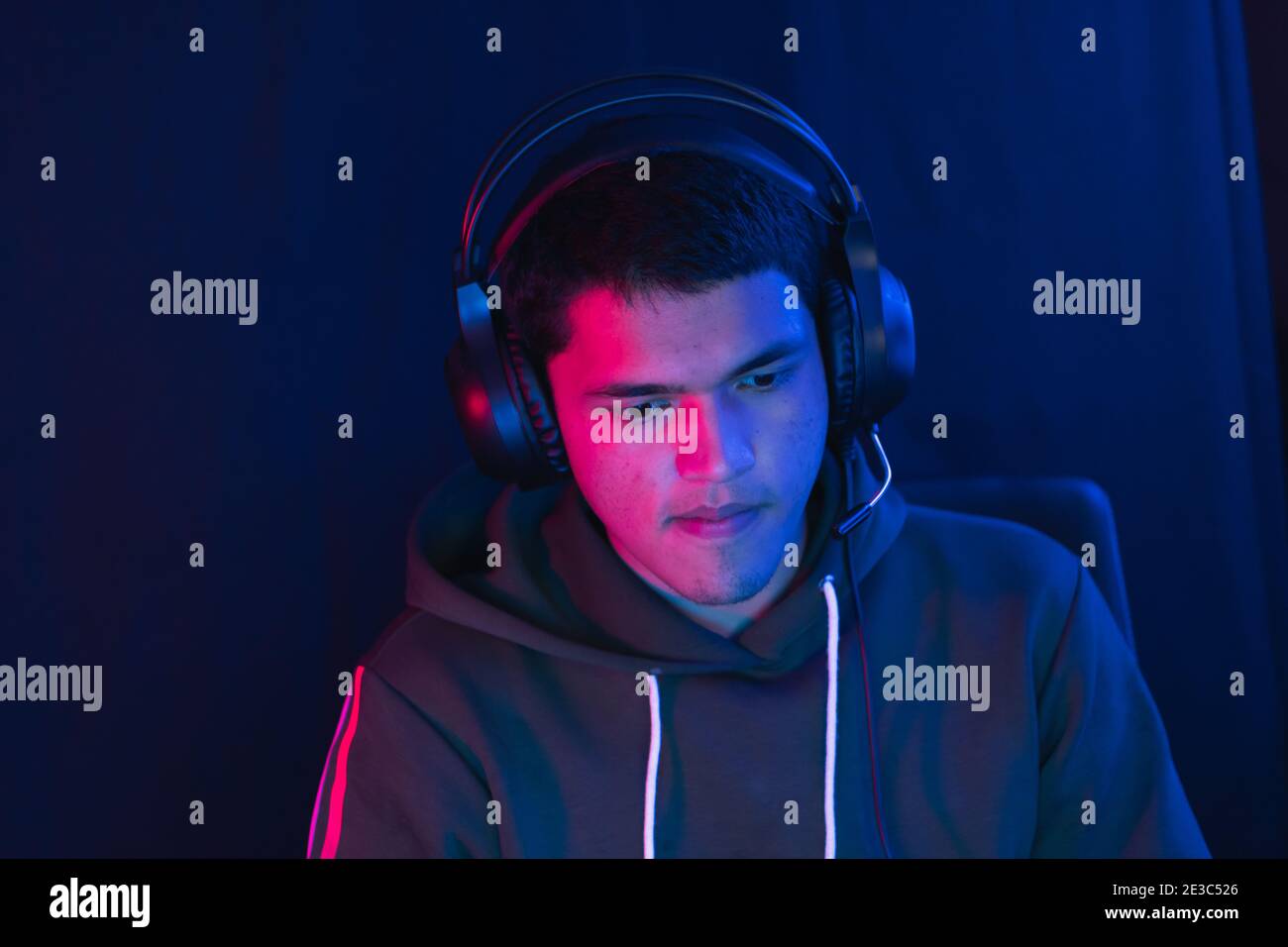Shallow focus of a Hispanic male gamer with headphones streaming an ...