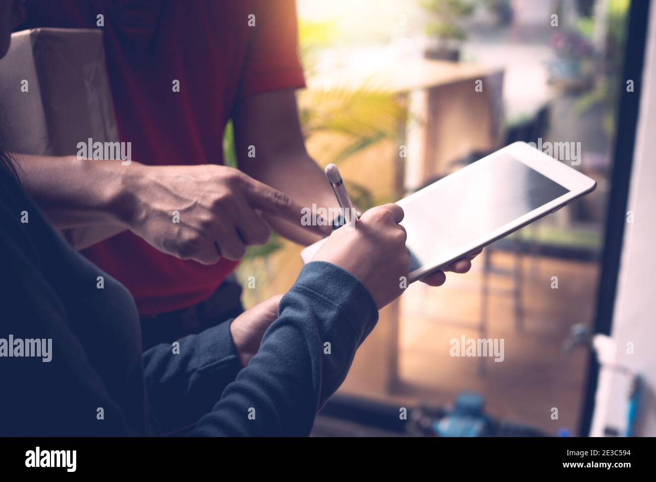 Customer sign name on tablet as getting box parcel from delivery man ...
