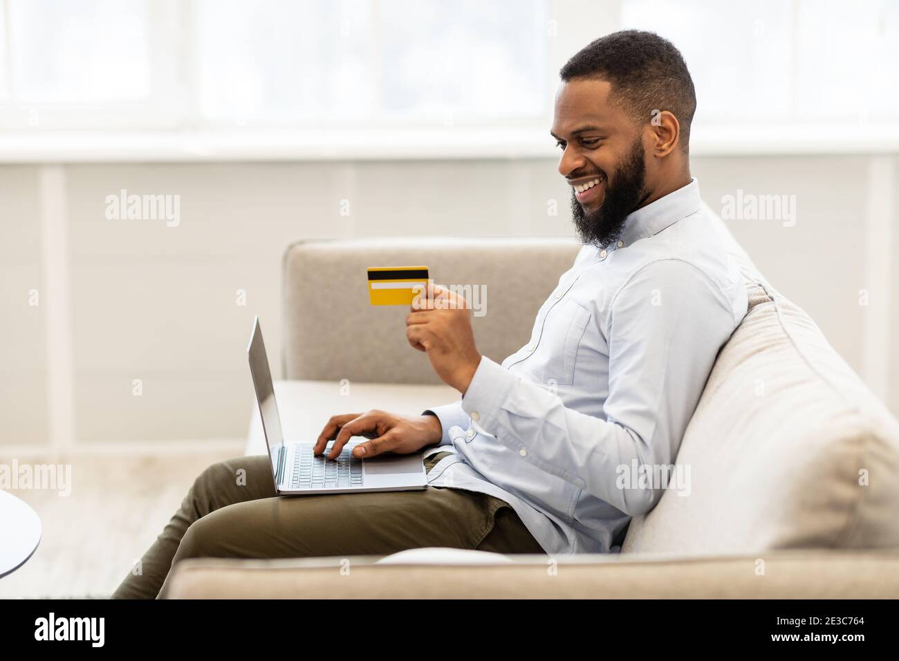 Black guy using laptop and debit credit card at home Stock Photo - Alamy
