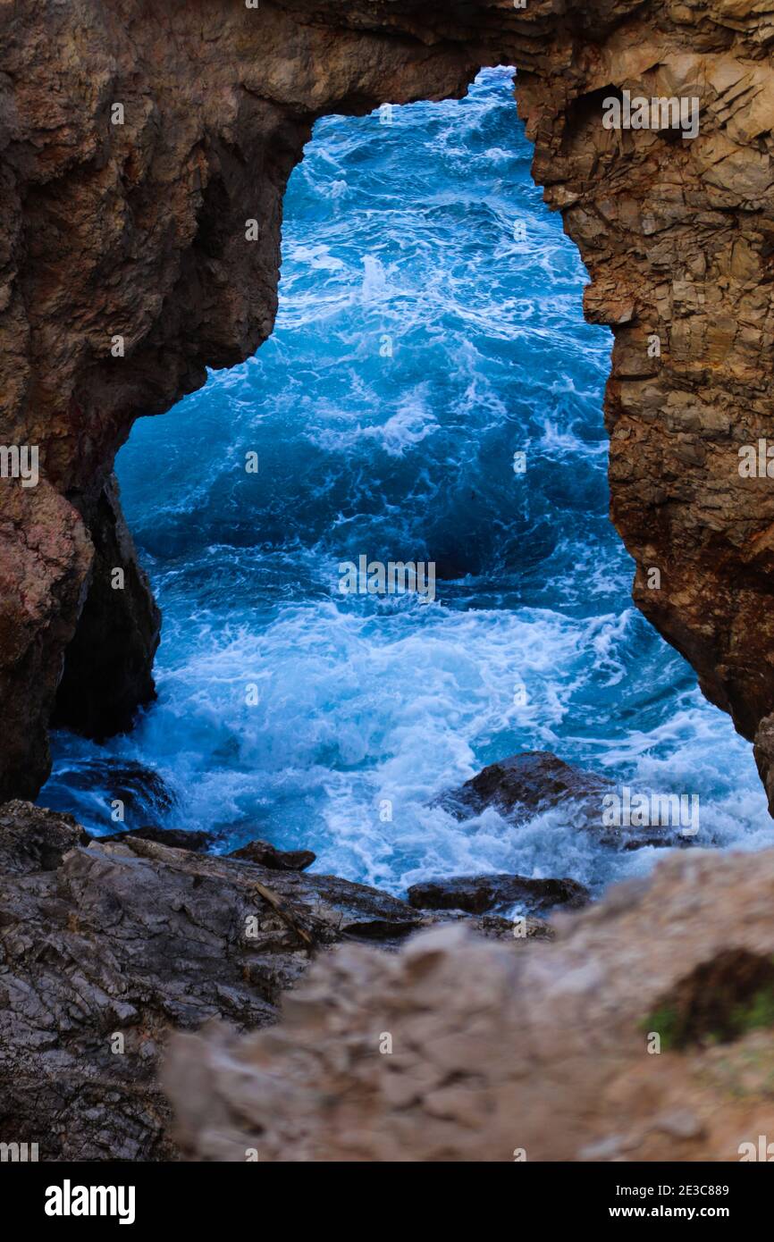 Vertical shot of the blue ocean opening from a rock view in Menorca ...