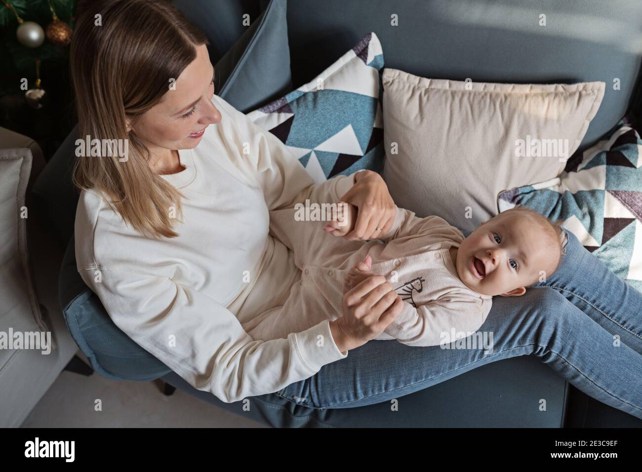 Young caucasian mother having fun on couch with baby at home during ...