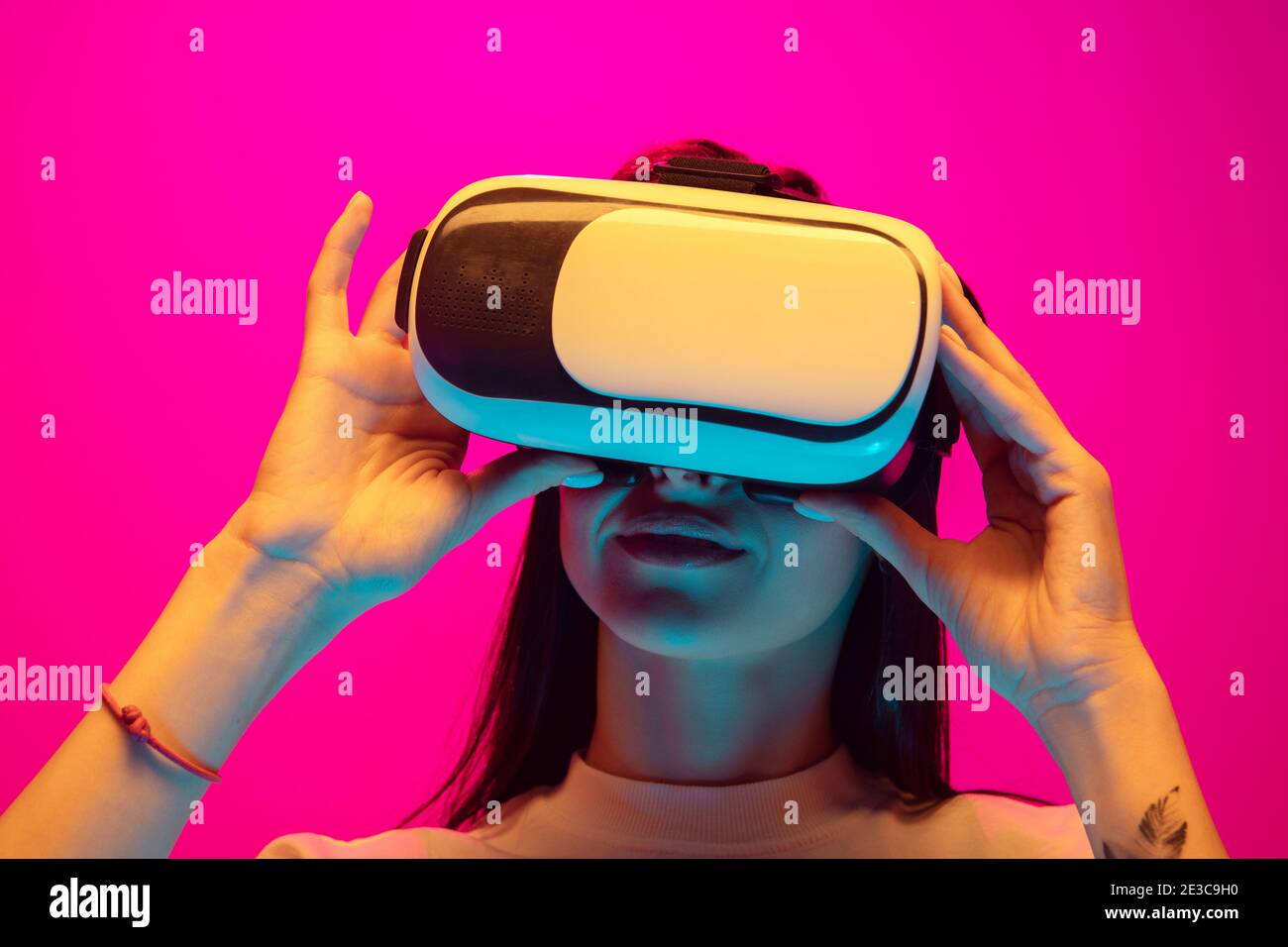 VR-headset. Caucasian woman's portrait isolated on pink studio ...
