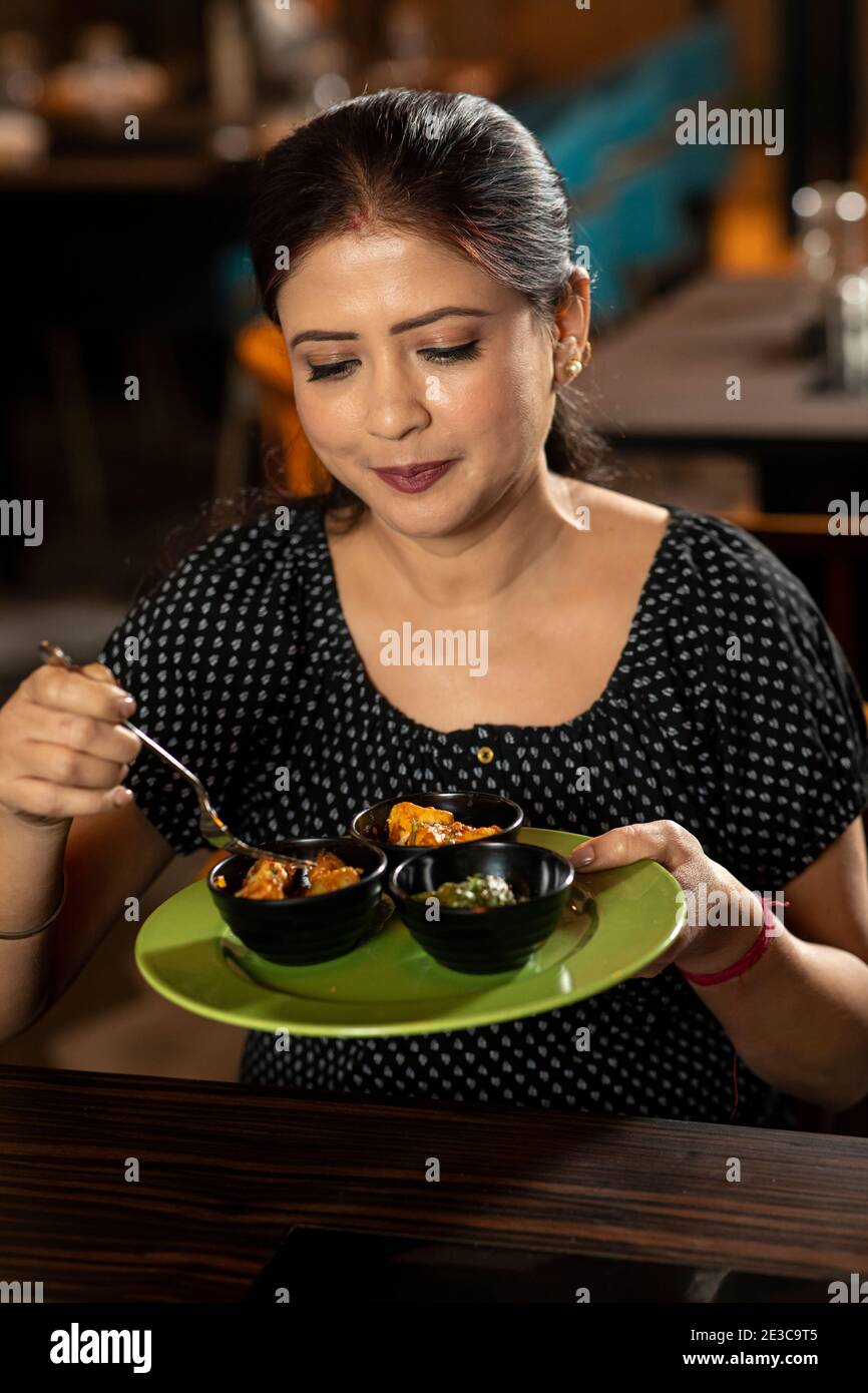 Portrait of a pretty woman eating delicious food in a restaurant Stock ...