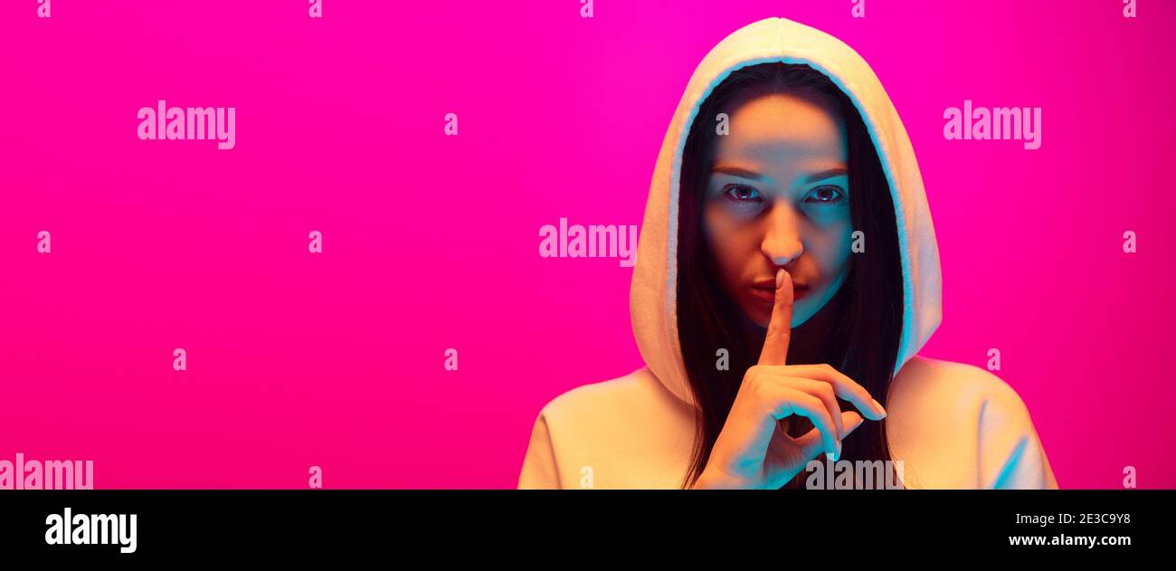 Secret. Caucasian woman's portrait isolated on pink studio background ...