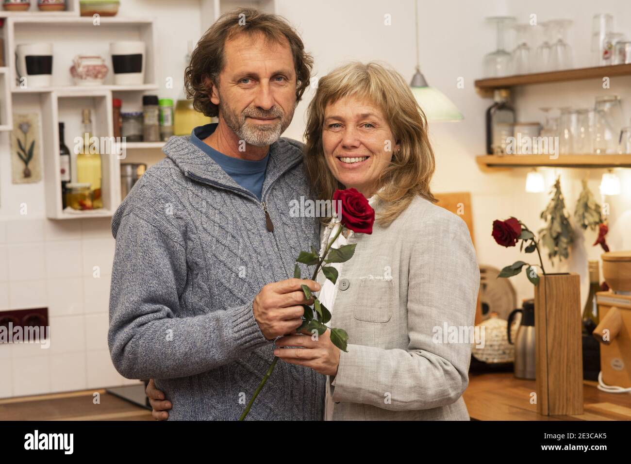 Selective focus shot of a middle-aged cute couple holding a red rose ...