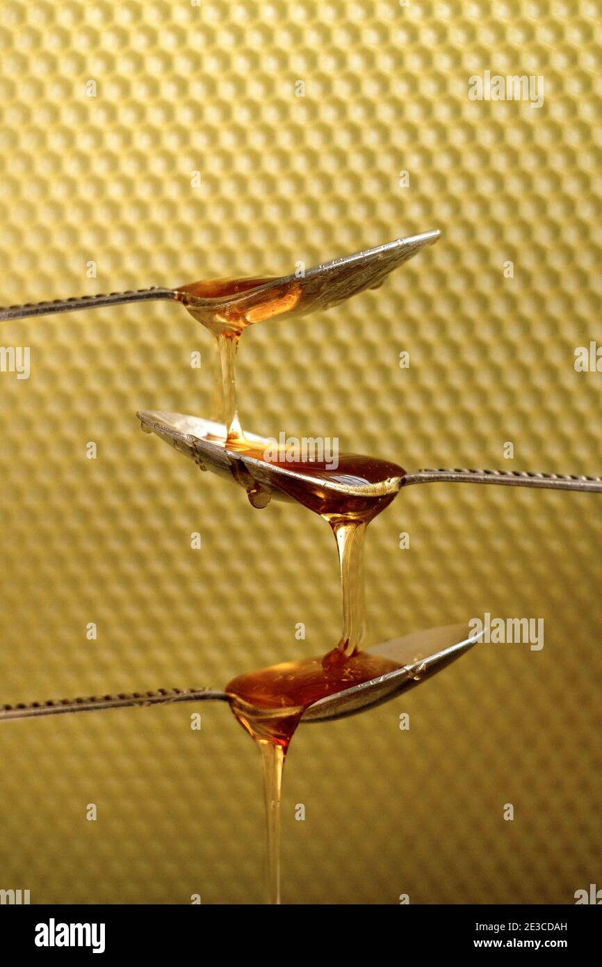 Spoons with raw honey on bee comb background, healthy nutrition concept ...