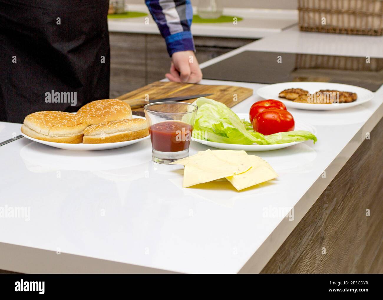Man in black apron prepares homemade burgers with ingredients, copy ...