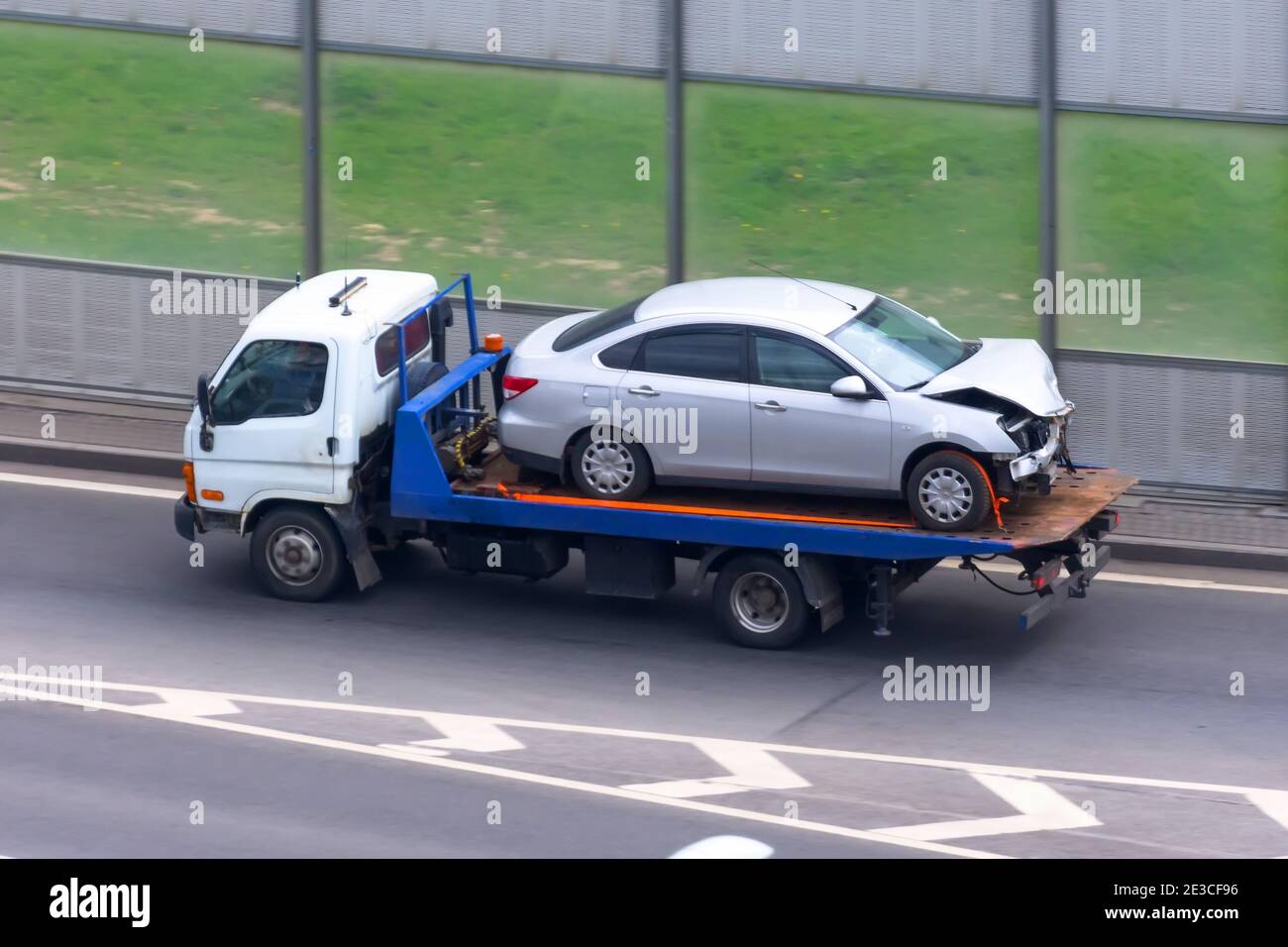 Crumpled car after an accident on a tow truck transported on a highway ...