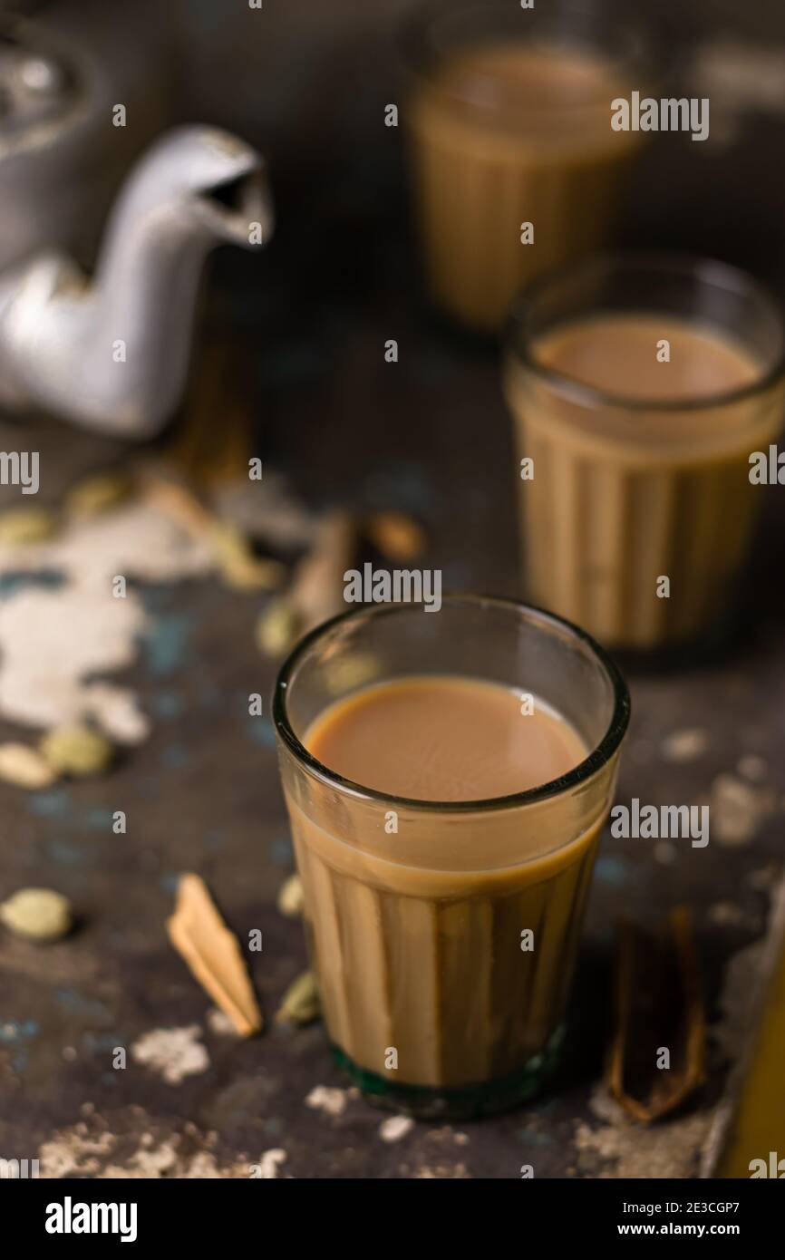 Indian chai in glass cups with metal kettle and other masalas to make ...