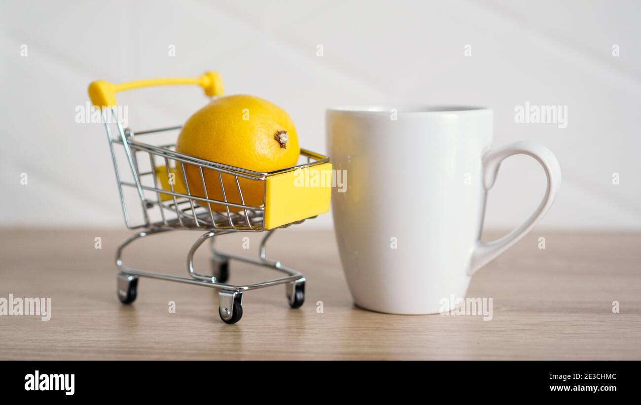 Lemon in a small shopping cart on the kitchen table. Nearby is a white ...