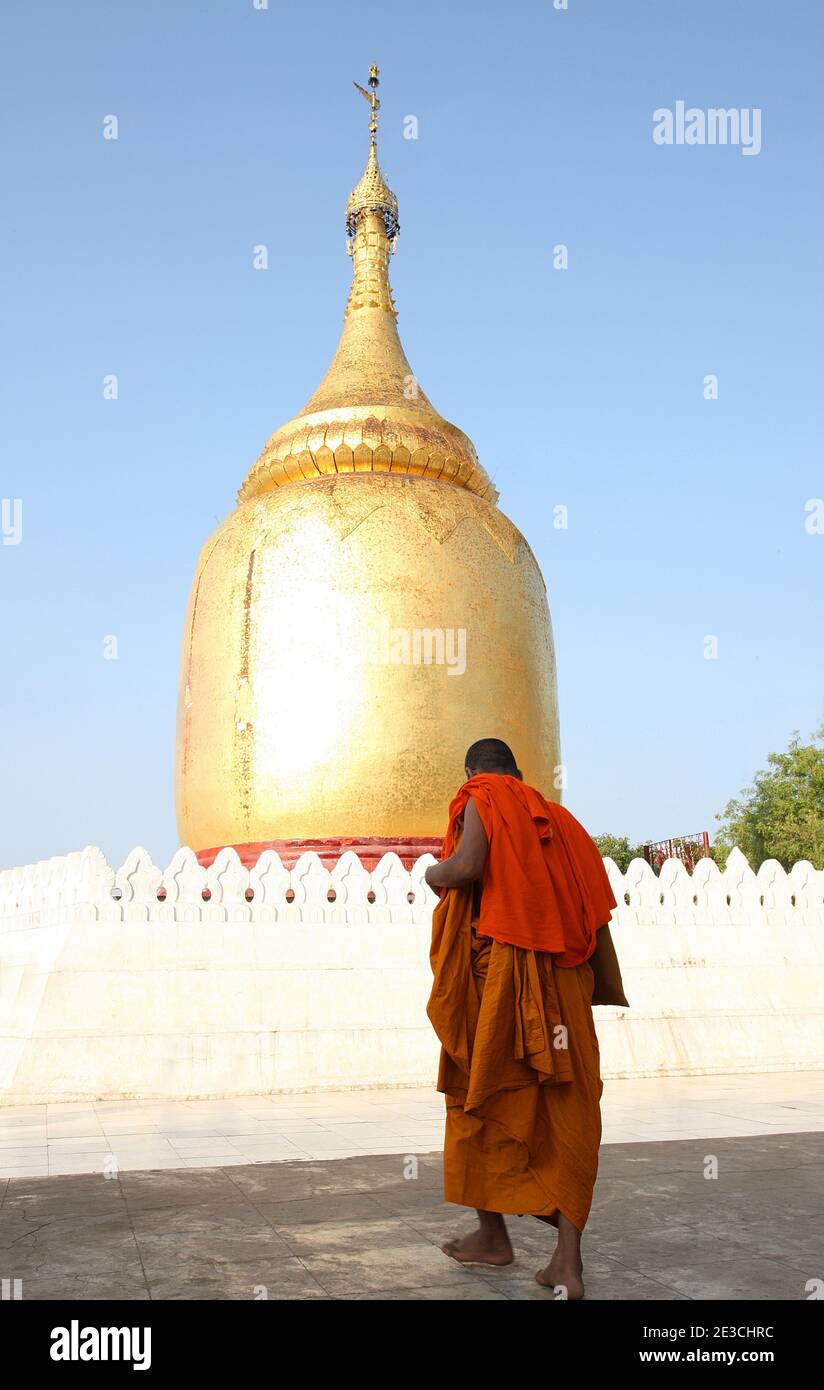 Buddhist Monk in orange and brown robes paying respects at the Bupaya ...