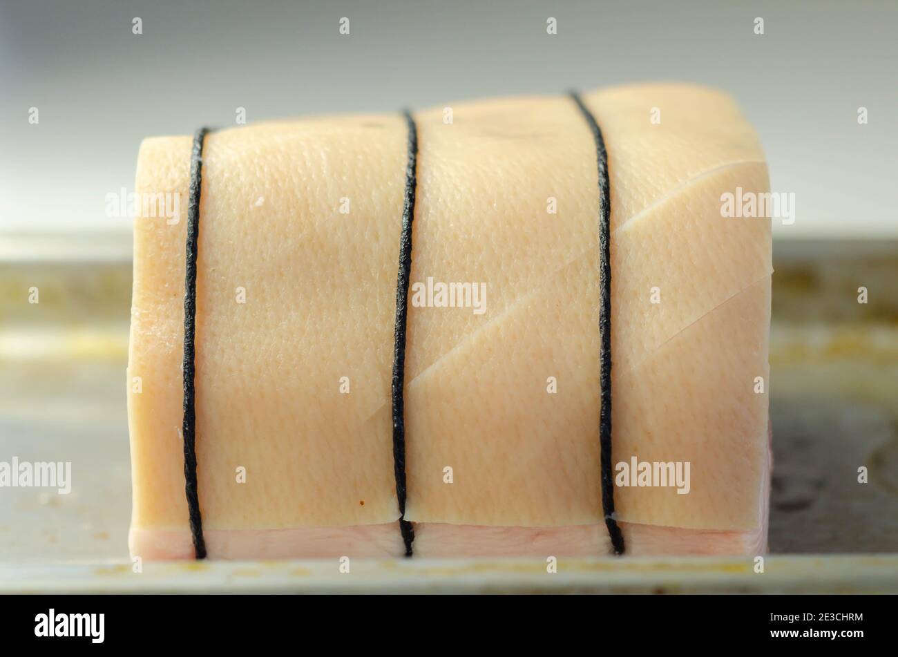 Boneless pork loin joint tied with string on the oven tray, raw meat ...