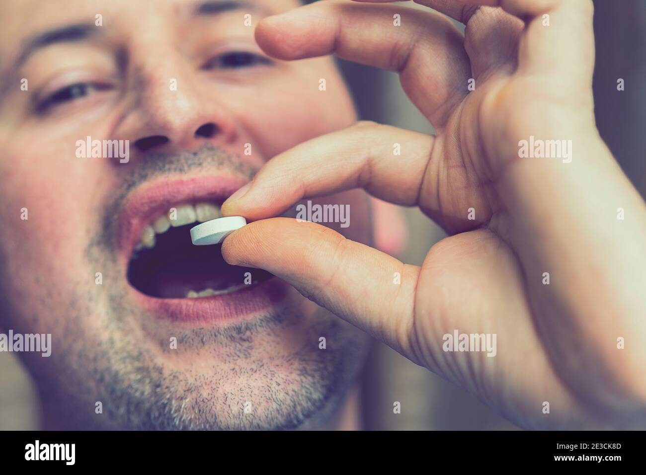 Extreme closeup man face taking white pill, mouth view swallowing pills ...