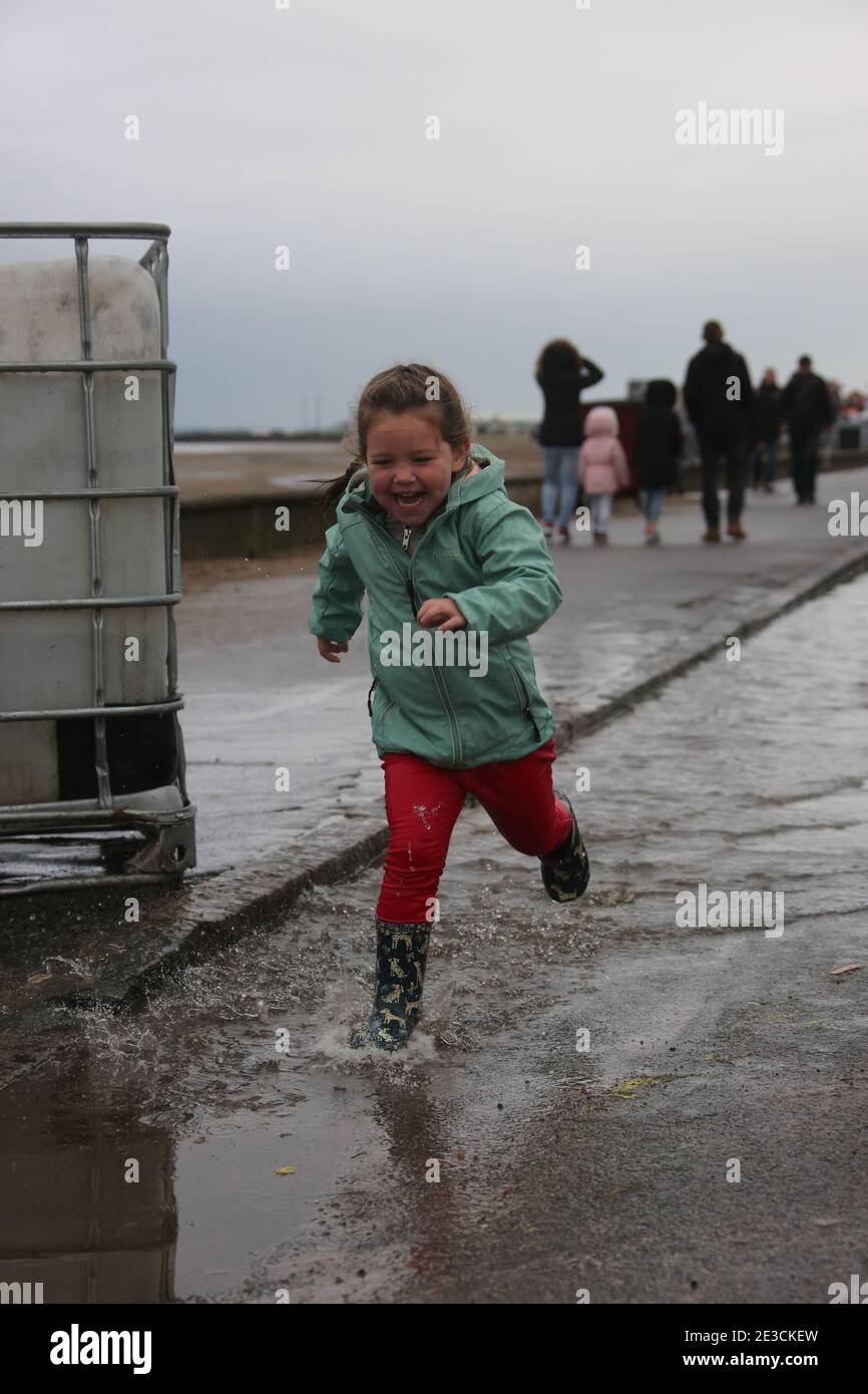 Young child having fun running through a puddle on Ayr Seafront ...