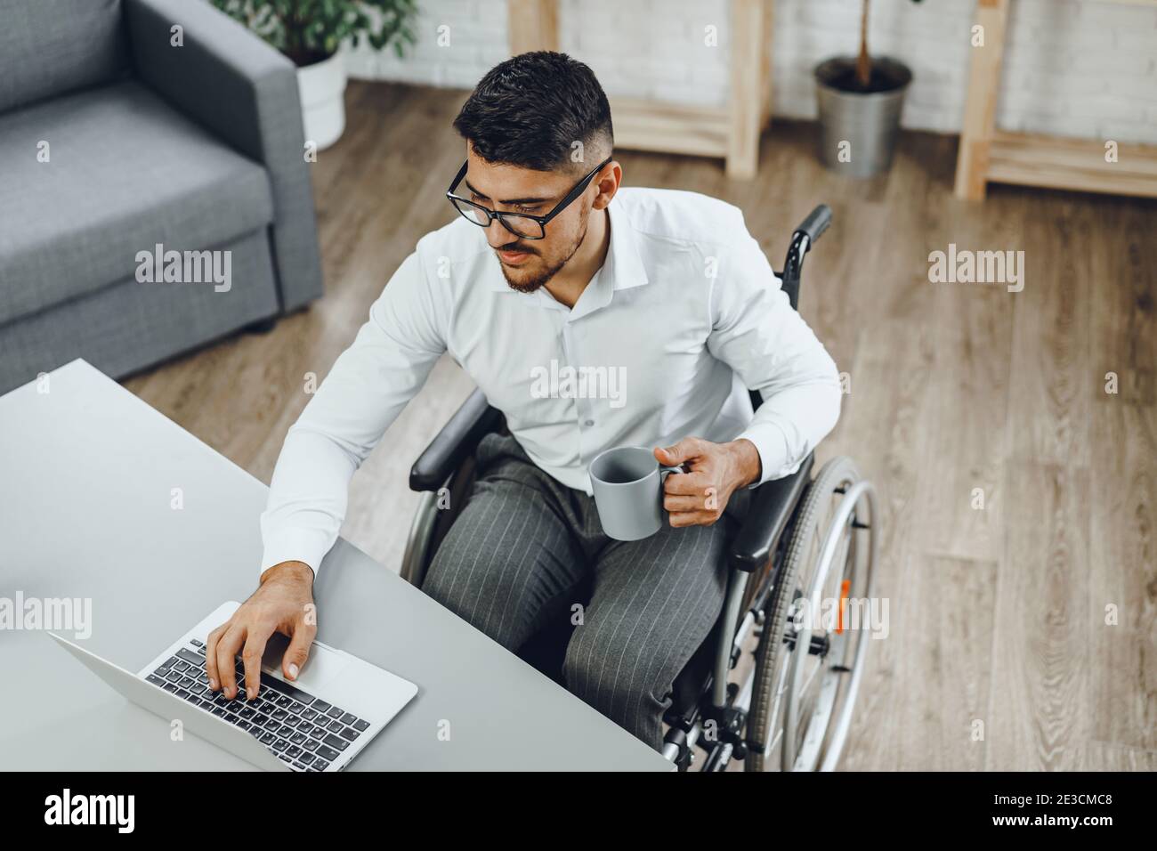 Positive disabled young man in wheelchair working in office Stock Photo ...