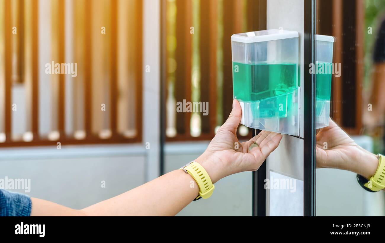 Close up to hands of senior woman pumping soap with green liquid soap ...