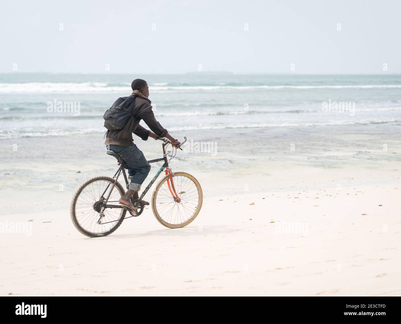 African young man riding bike on tropical beach Stock Photo - Alamy