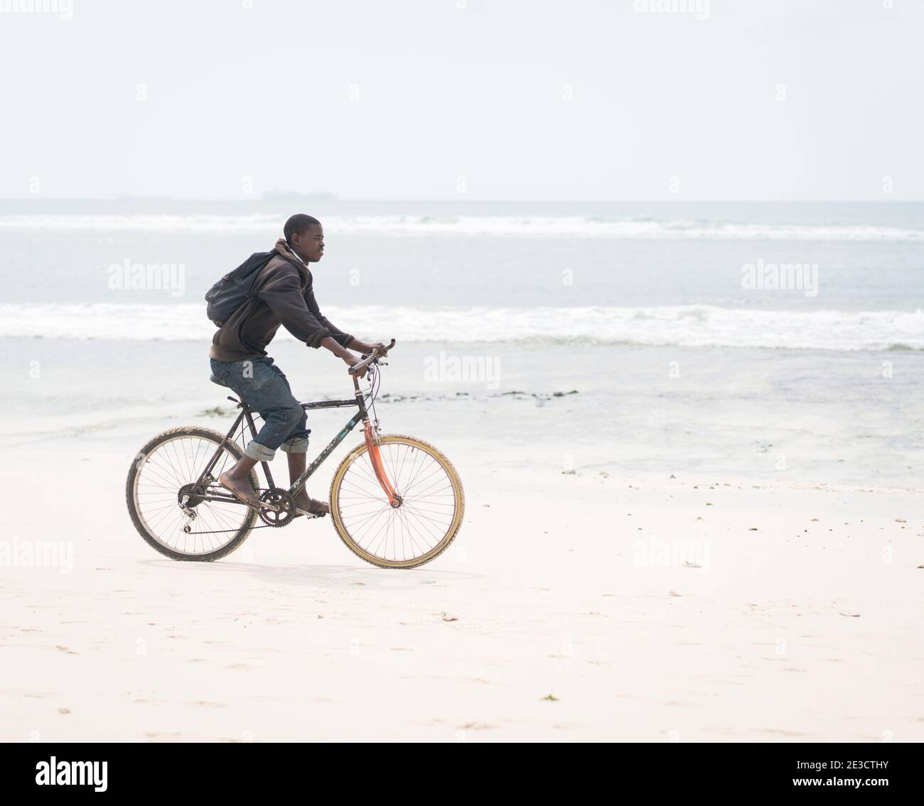 African young man riding bike on tropical beach Stock Photo - Alamy