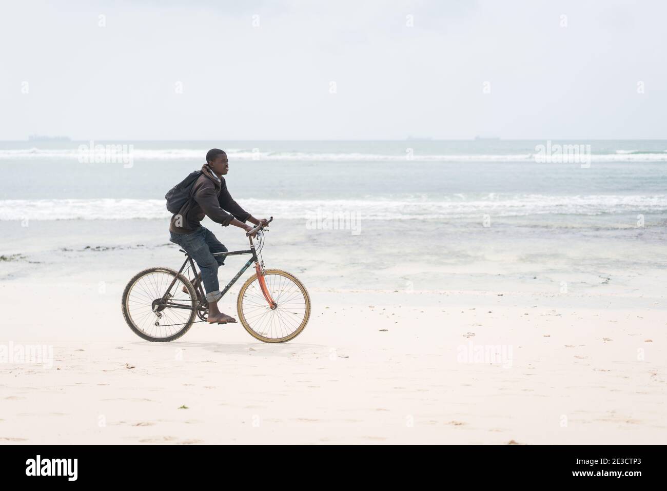 African young man riding bike on tropical beach Stock Photo - Alamy