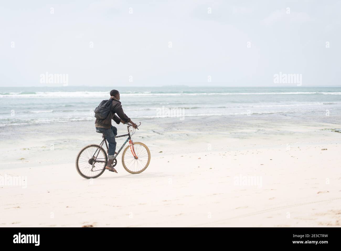 African young man riding bike on tropical beach Stock Photo - Alamy