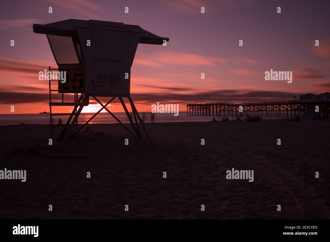 Pink dramatic sunset with lifeguard tower and pier Stock Photo - Alamy
