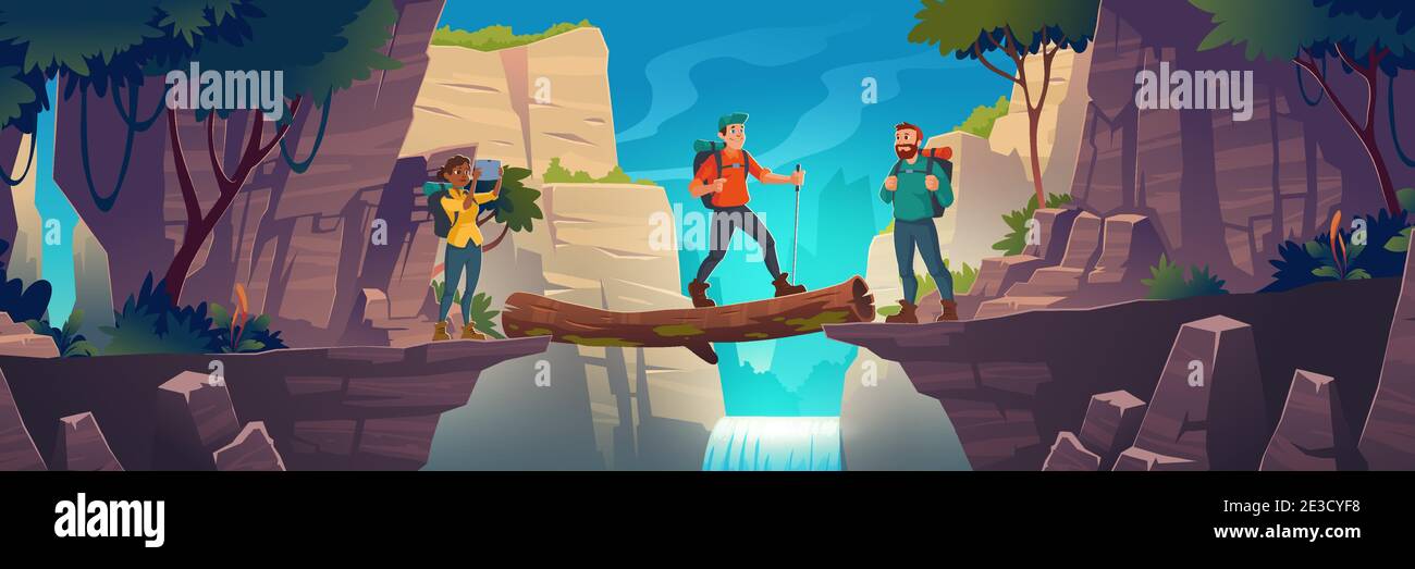 Tourists cross log bridge between mountains above cliff in rock peaks ...