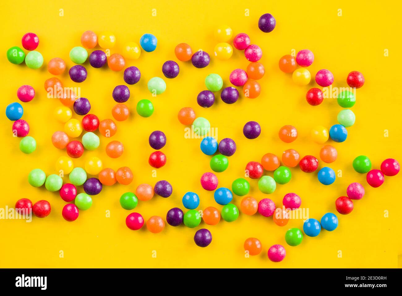 Skittles candy on the yellow table, colorful sweet candy background ...