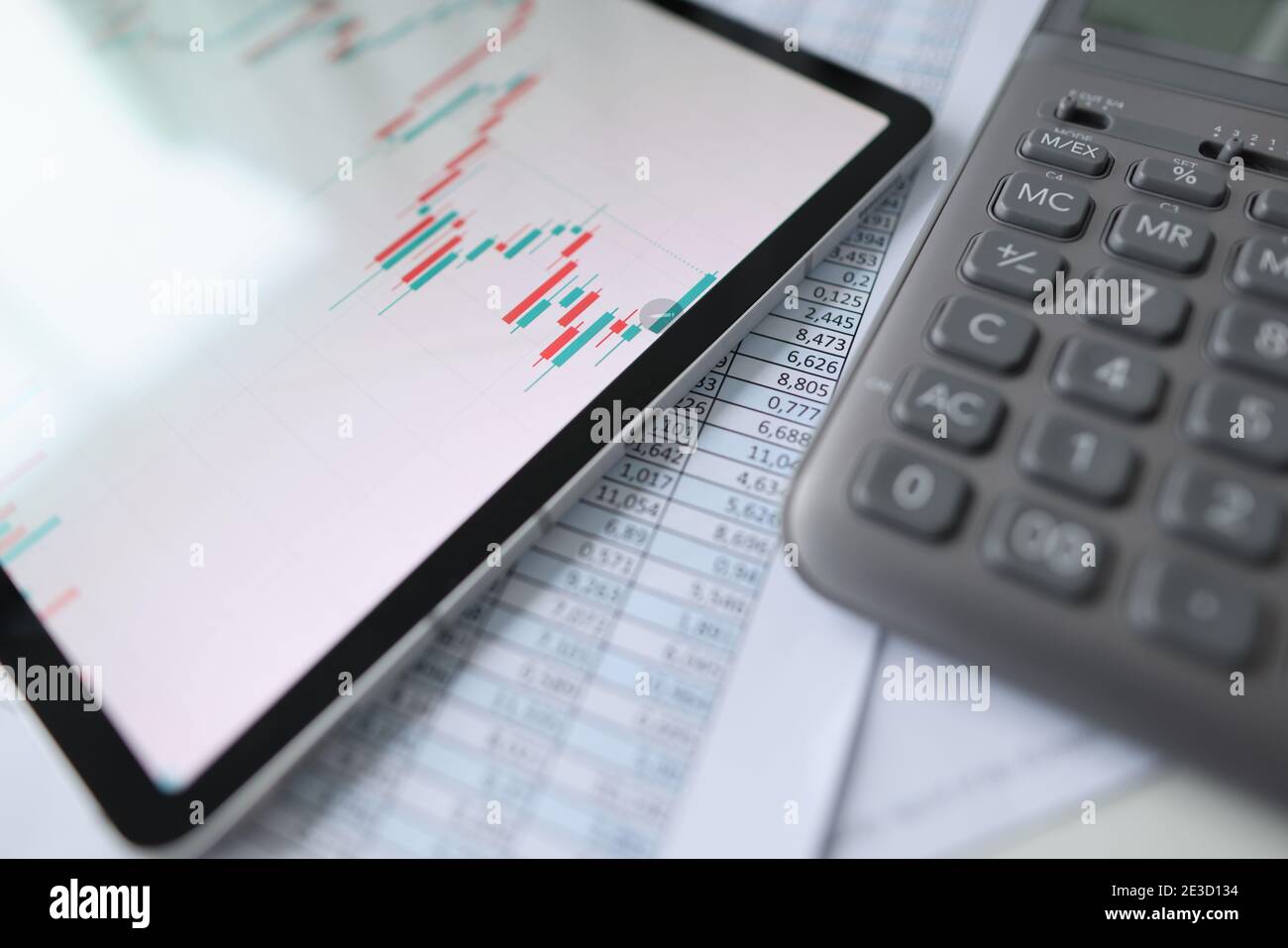 On table is tablet with commercial charts, calculator and documents ...
