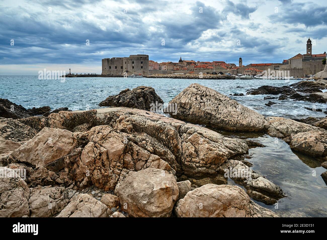 Coastal rocks and medieval defensive walls in the city of Dubrovnik in ...