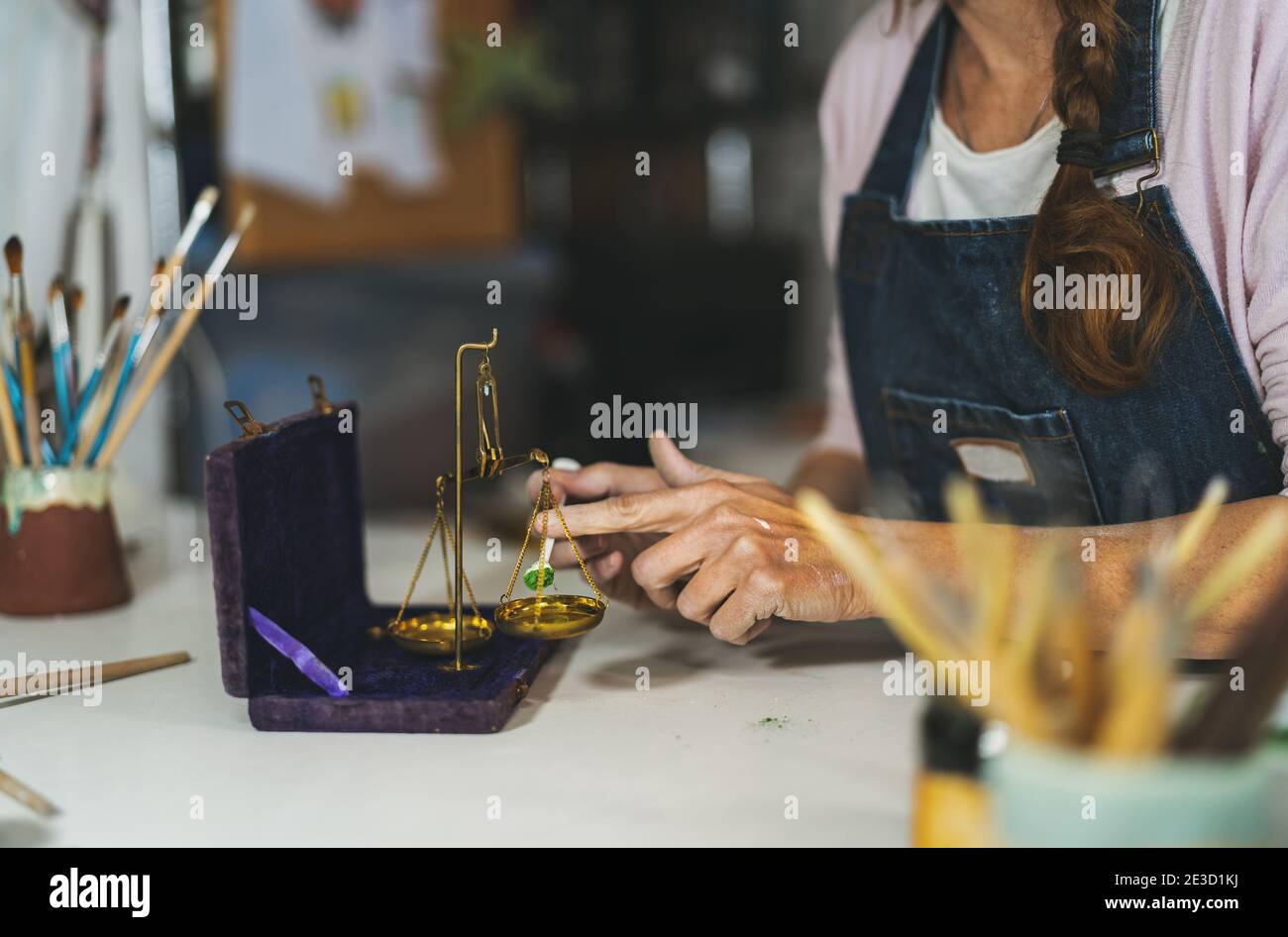 Happy woman pouring paint colors powder on vintage balance in pottery ...
