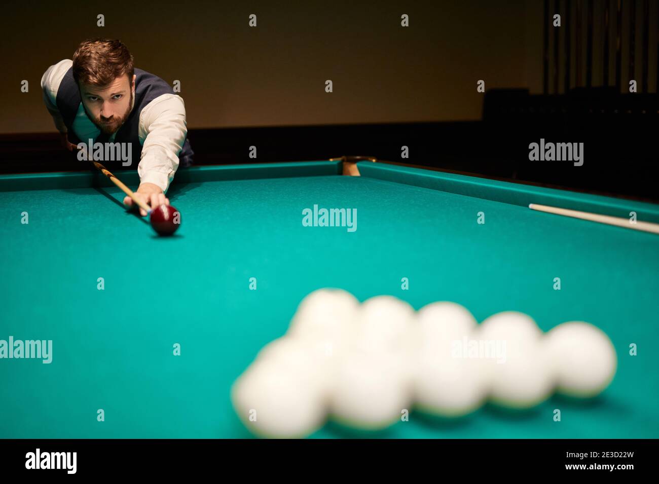 man is playing snooker, he is aiming to shoot the snooker ball ...