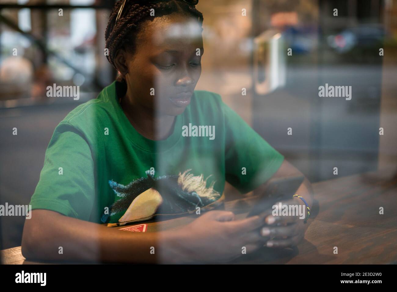 Young authentic black woman sitting with phone in city coffee shop ...