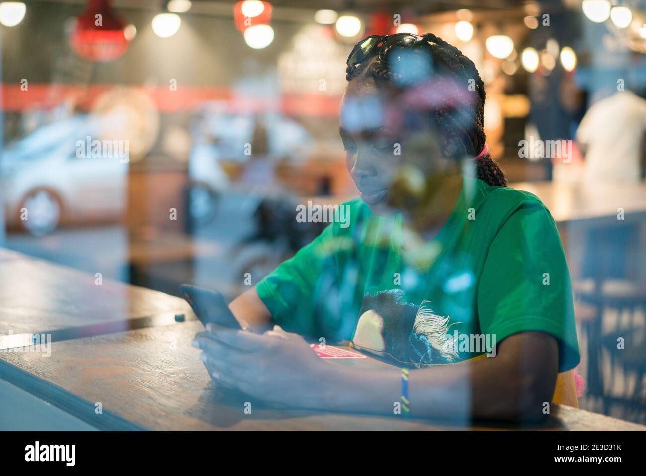 Young authentic black woman sitting with phone in city coffee shop ...